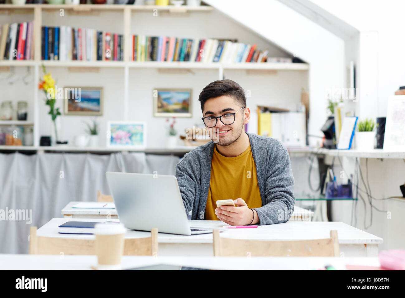 Handsome student sitting by desk in classroom Stock Photo - Alamy