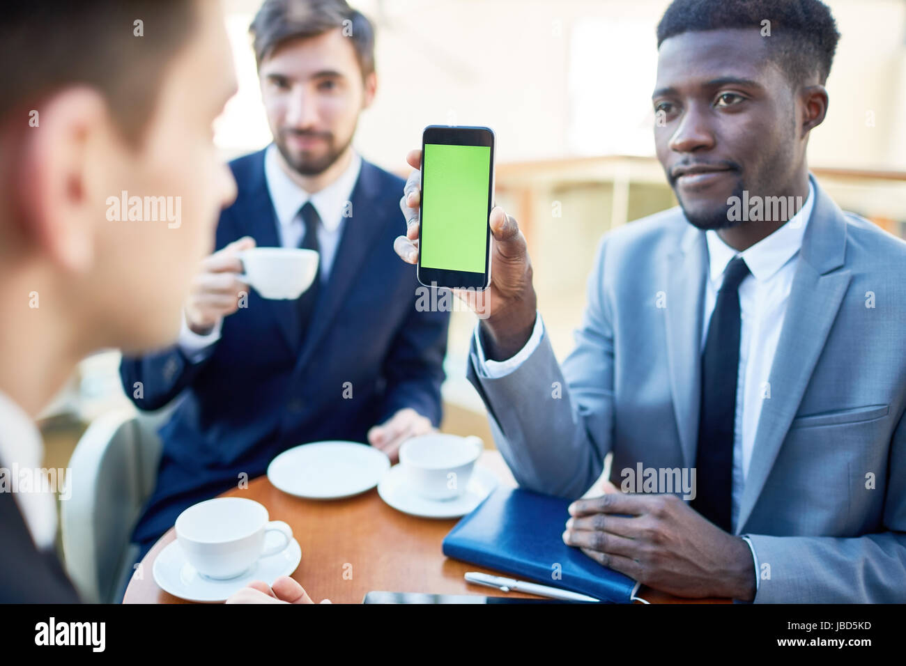 Confident employee showing touchscreen of smartphone to colleague Stock ...