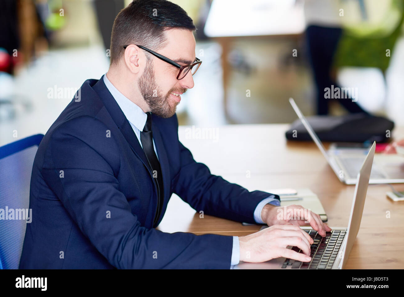 Happy businessman typing by his workplace Stock Photo - Alamy