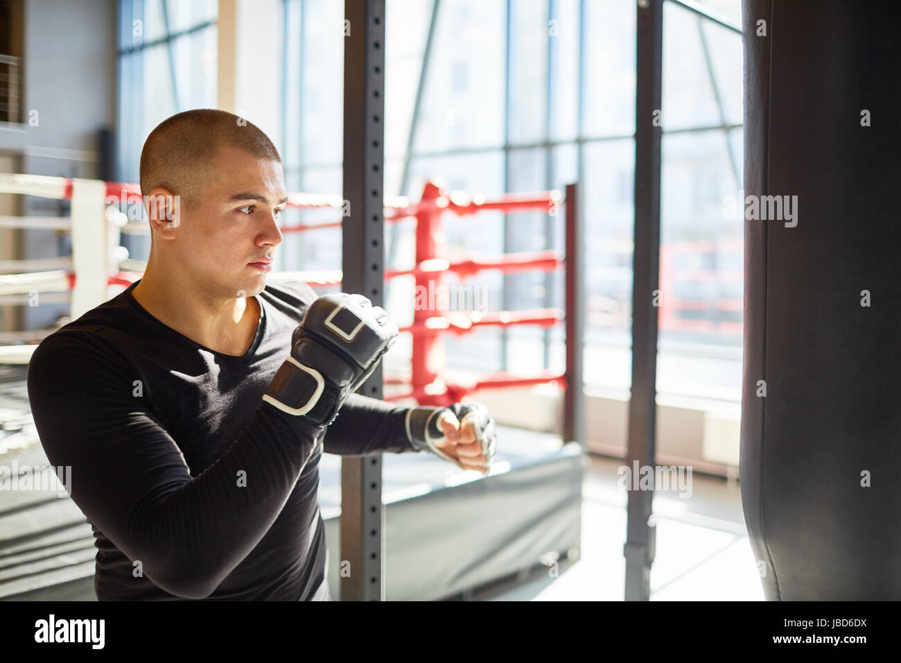 Portrait of young muscular sports man hitting punching bag during ...