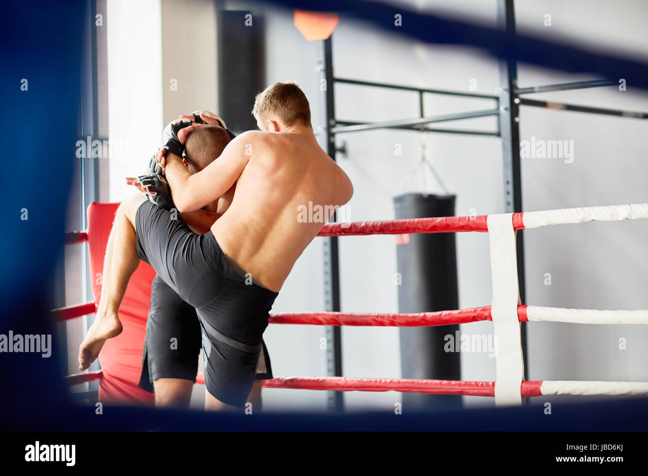 Portrait of shirtless wrestler fighting with opponent in boxing ring ...