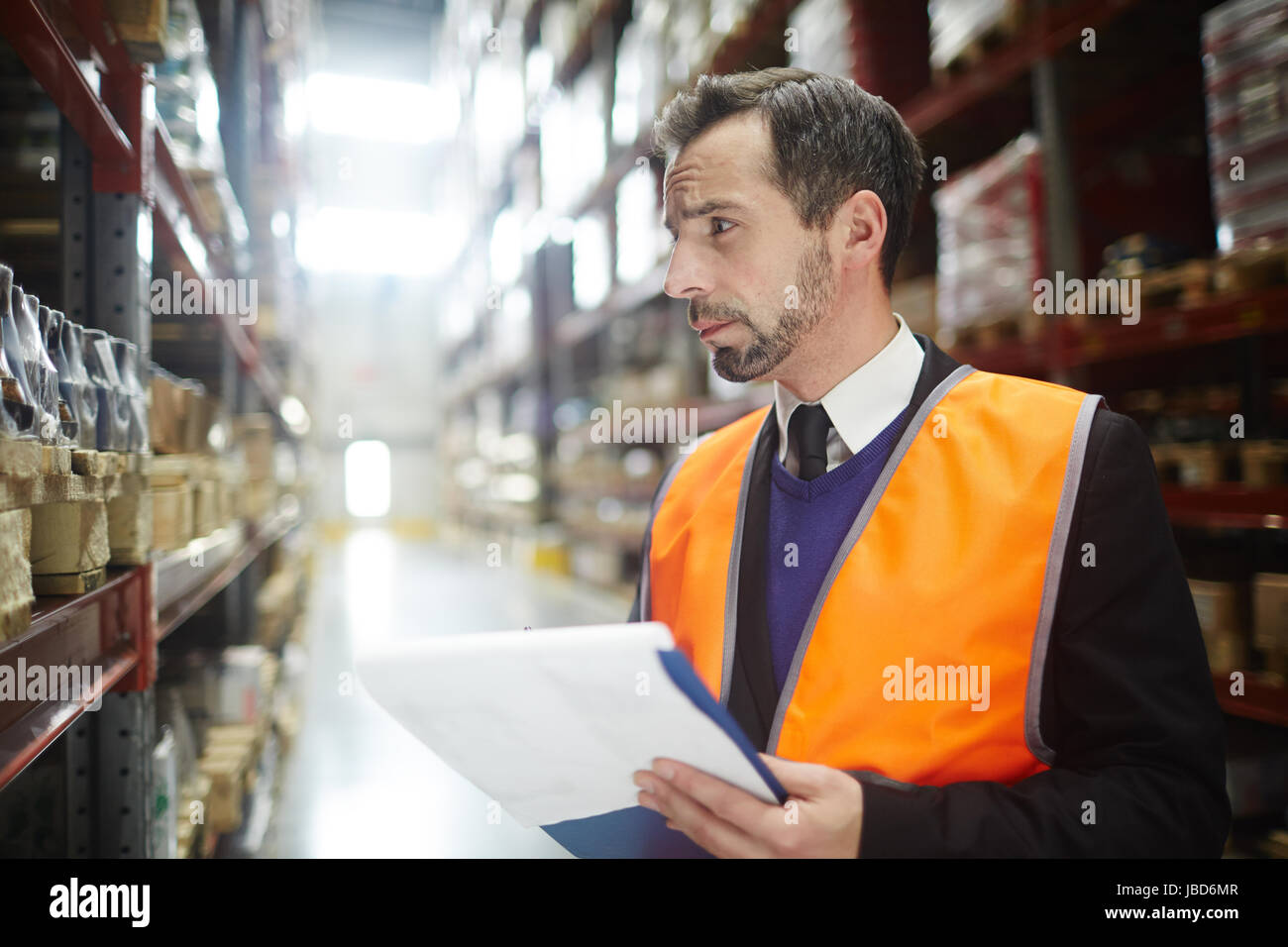 Young man making list of goods in storehouse Stock Photo - Alamy