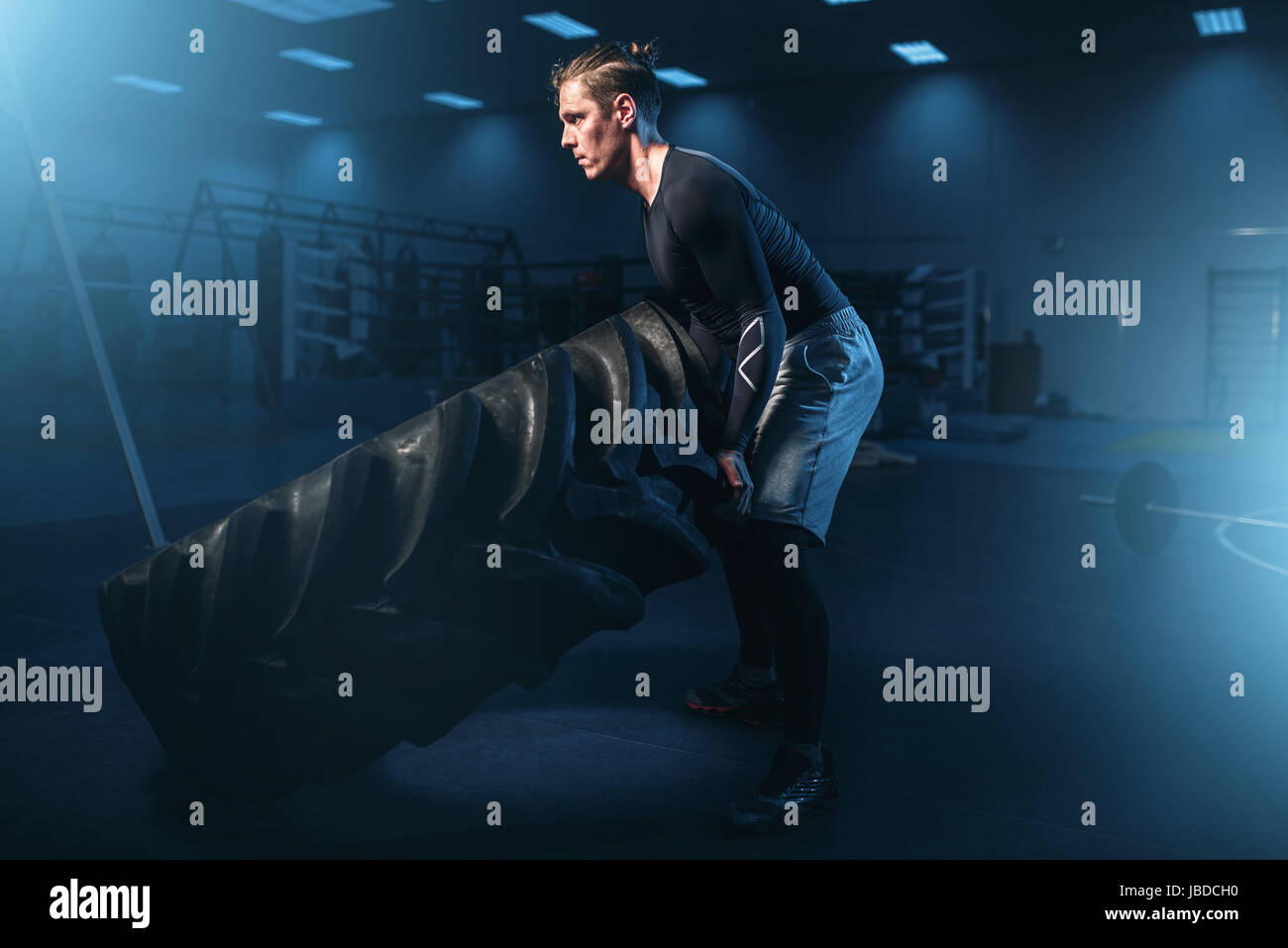 Male athlete on training, workout with heavy tire in gym. Energy ...