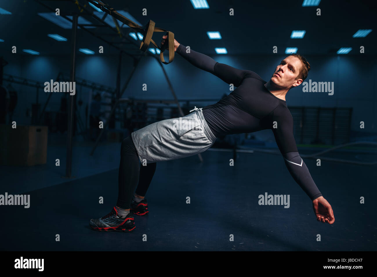 Male athlete on training, stretch workout with ropes in gym. Energy ...