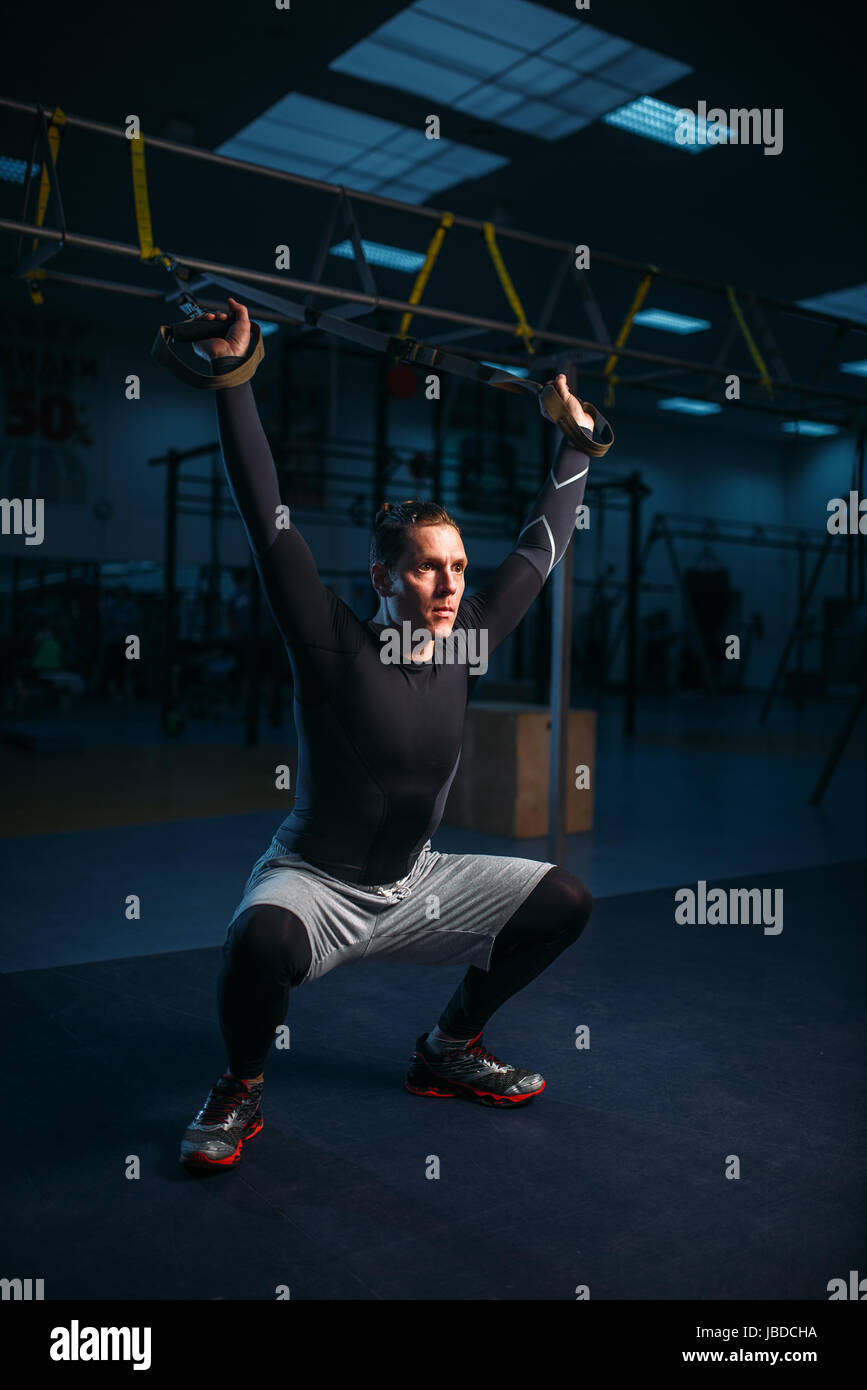 Strong sportsman on training, stretch endurance workout with ropes in ...