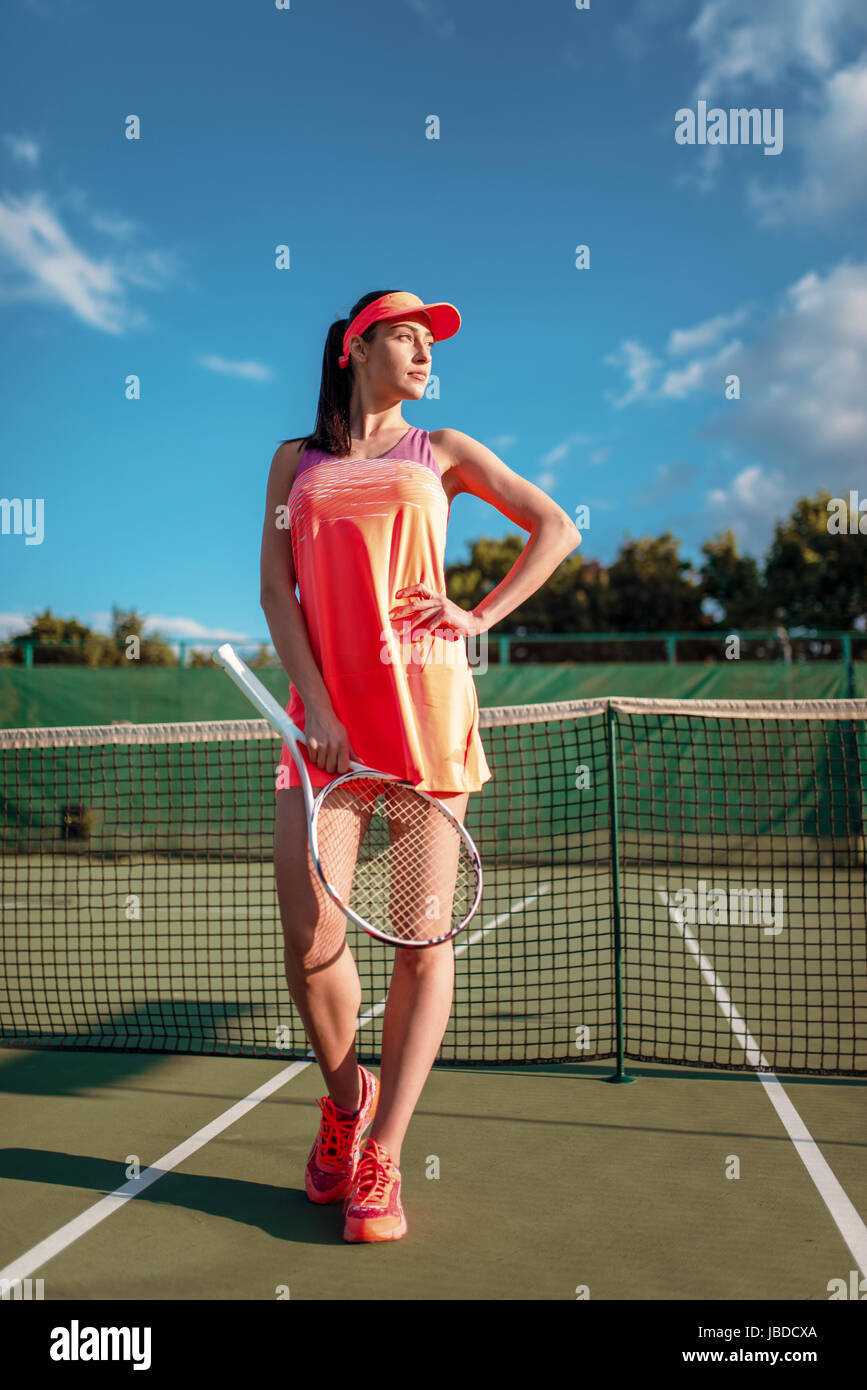 Athletic woman with tennis racket poses on outdoor court. Summer season ...