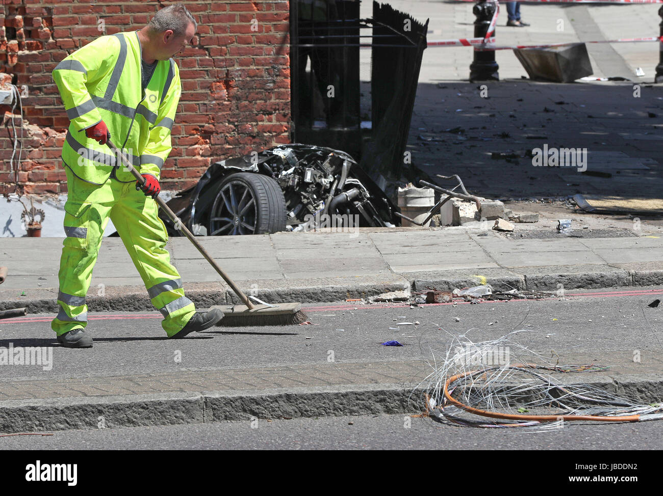 Workers clean up the scene of a car crash in Kensington, London where a ...