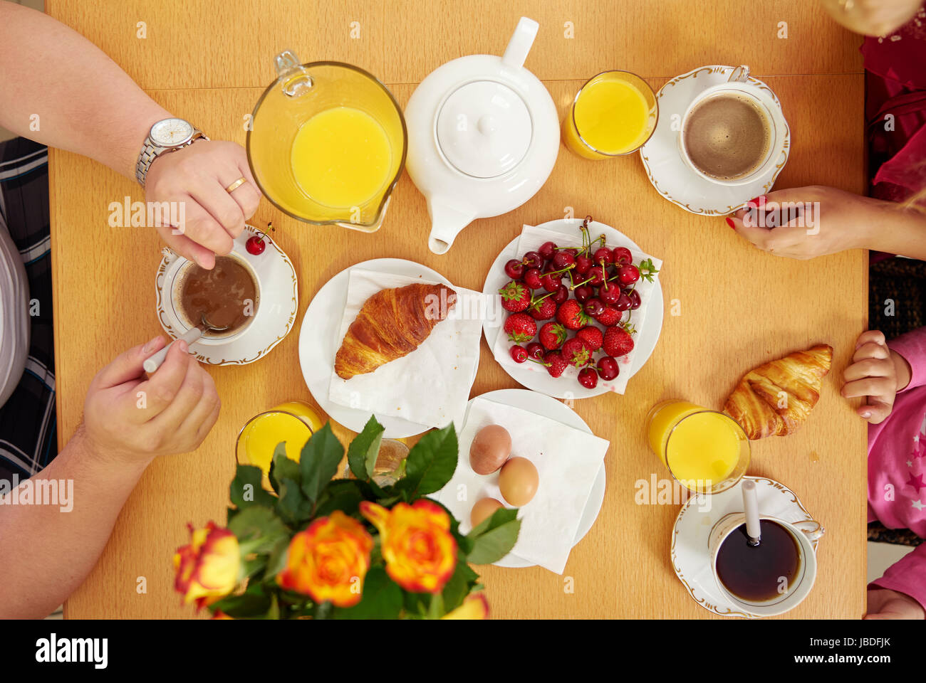 Top view of a family breakfast with croissants, berries, coffee and ...