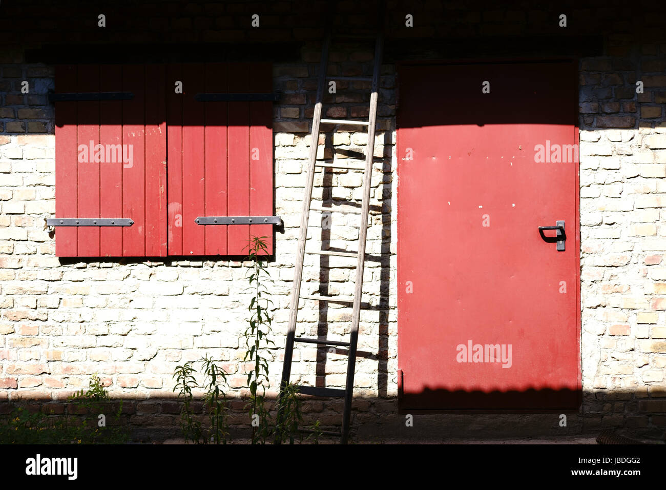 A ladder leaning against a barn in the sunlight with a wooden door and ...