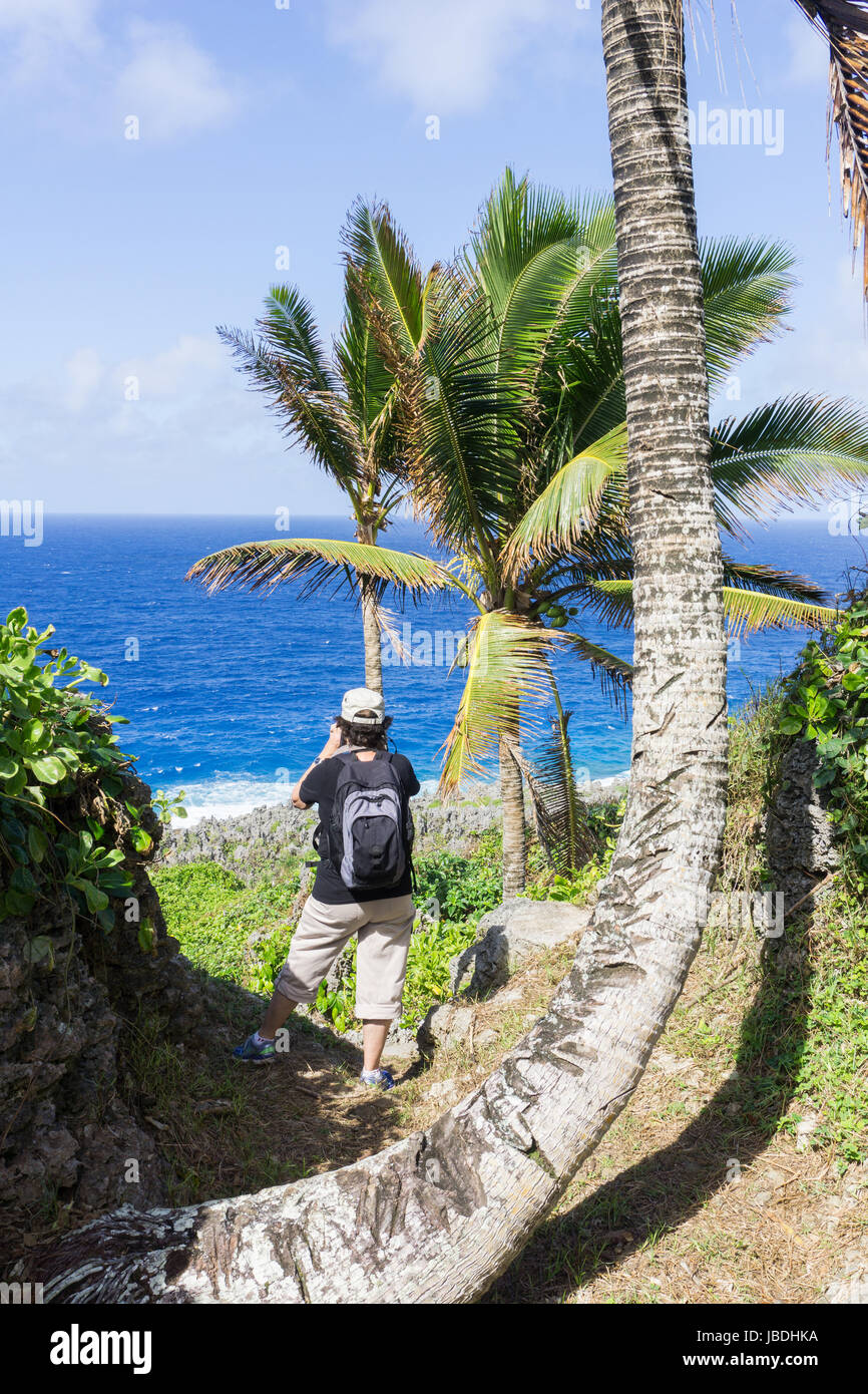 Tourist photographs rugged and jagged coastal feature of coral along ...