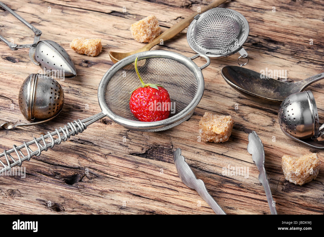 tea-spoons, spoon for tea-leaf, sieve with strawberry on retro ...