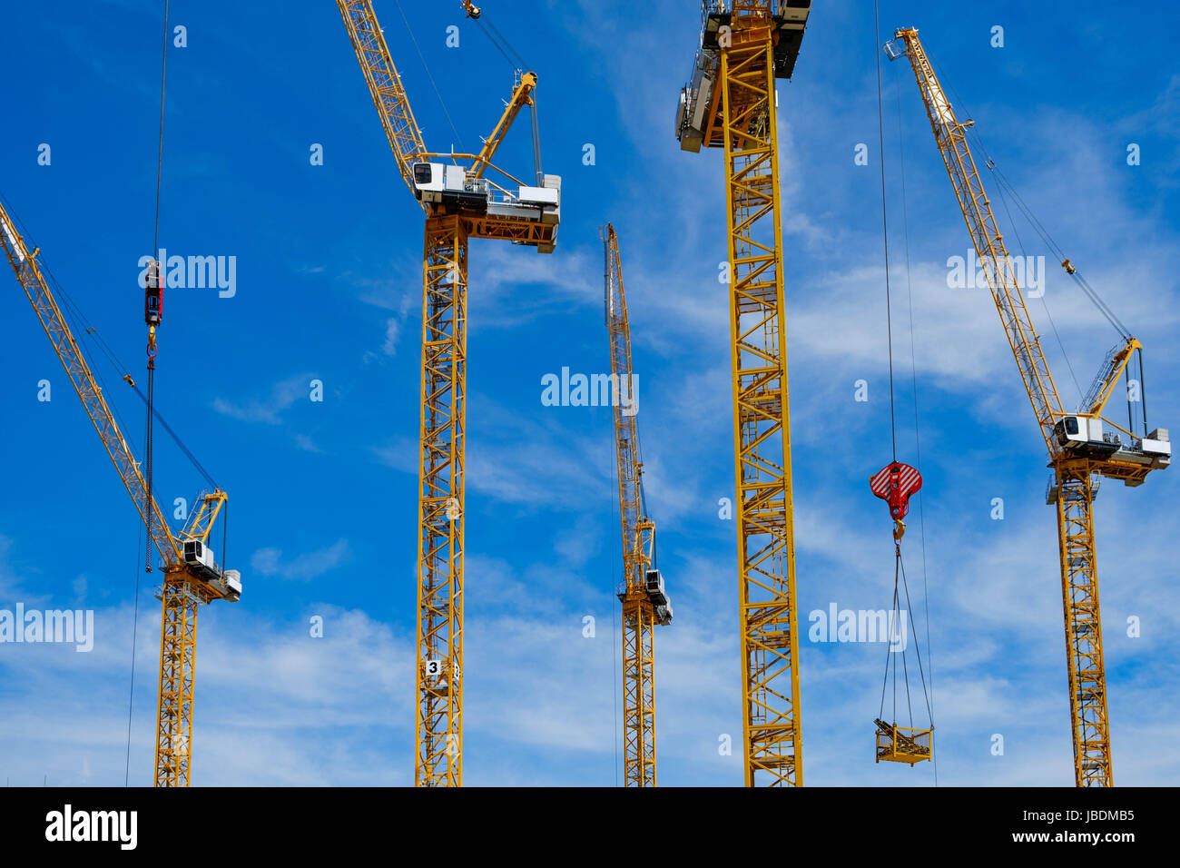 many yellow construction cranes on blue sky backgrounds Stock Photo - Alamy