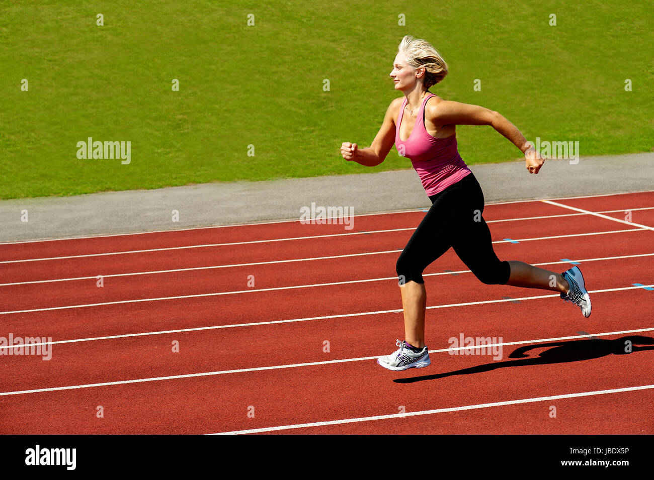 Middle aged athlete running down the track Stock Photo - Alamy
