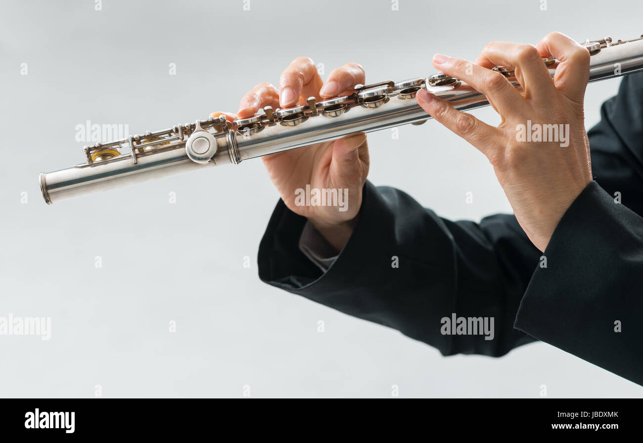 Professional elegant female flutist performing in a white room, hands ...