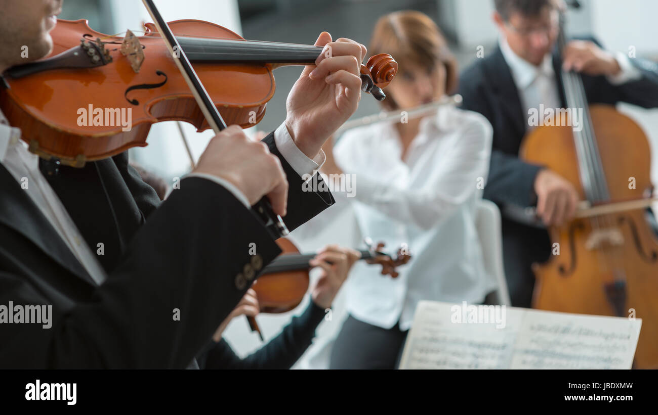 Confident violinist playing his instrument and reading a music sheet ...