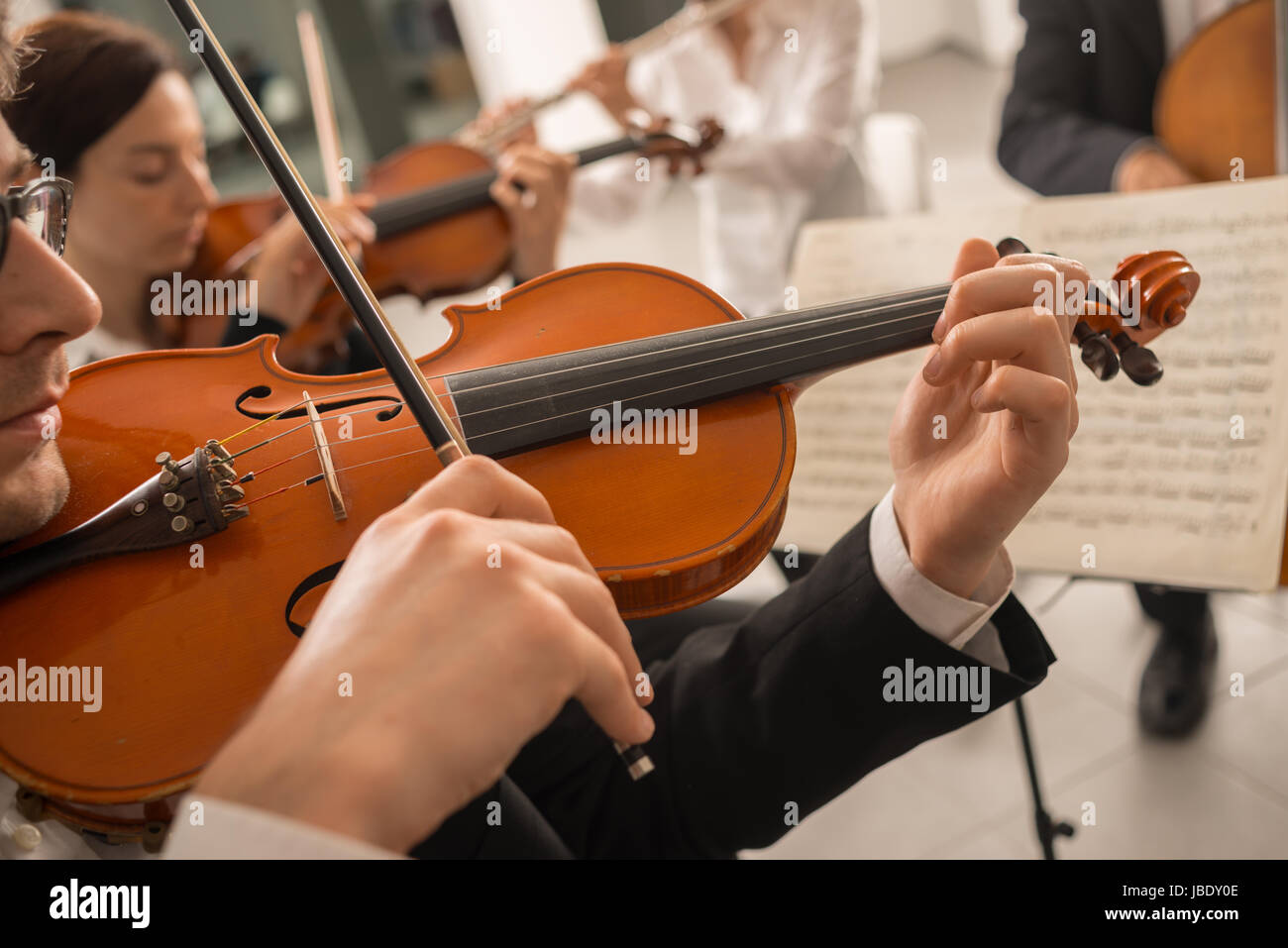 Confident violinist playing his instrument and reading a music sheet ...