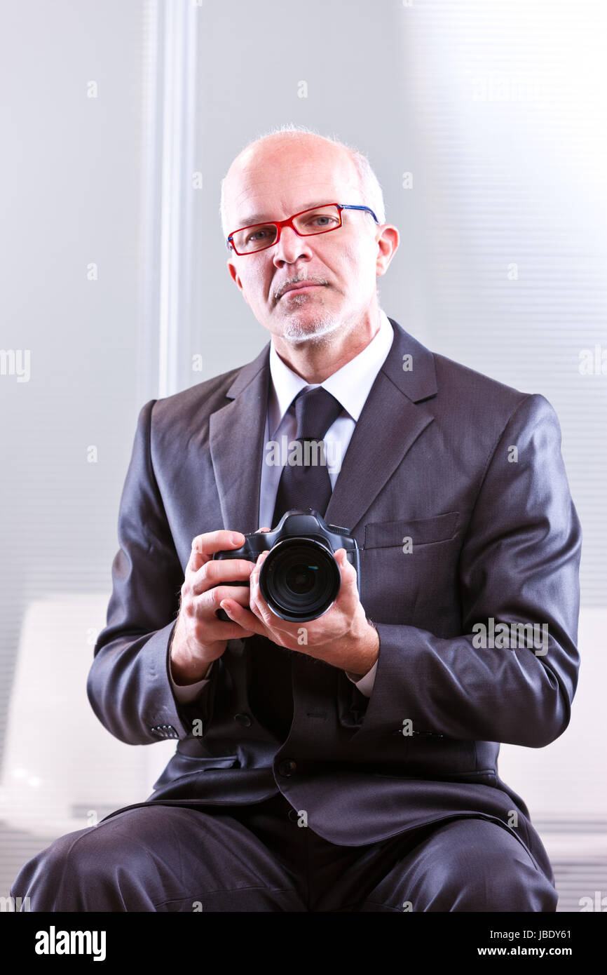 elegant man looking at camera with a DSLR camera in his hands Stock ...