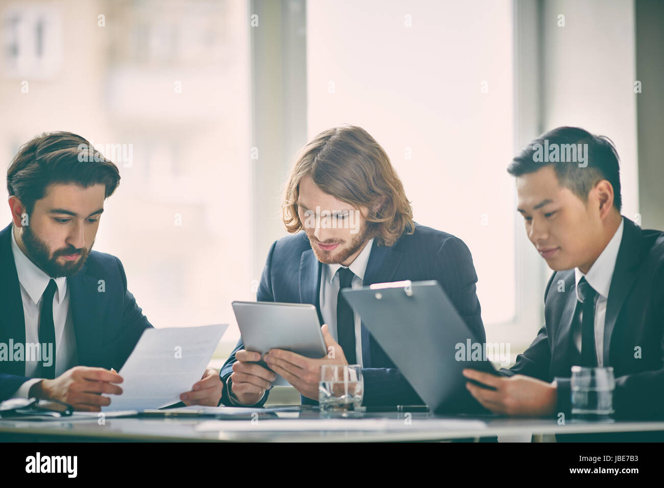Portrait of three partners at meeting table Stock Photo - Alamy
