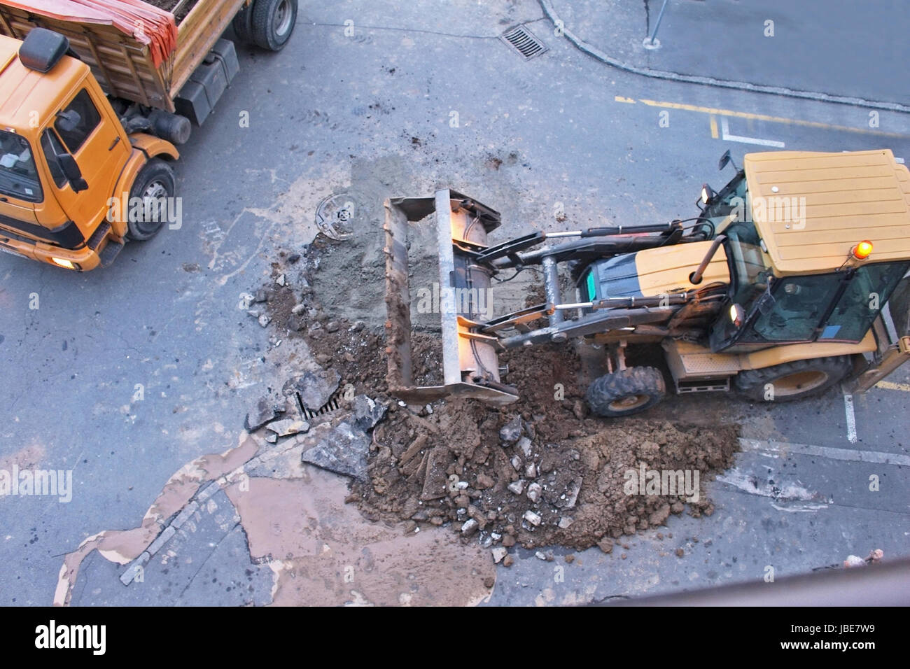 Excavator machine digging hole on urban road Stock Photo - Alamy