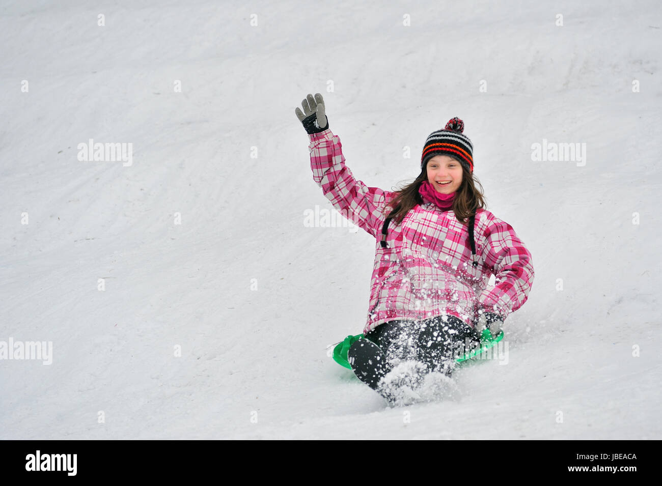 Happy girl sliding on sled with her hands lifted in the mountains Stock ...