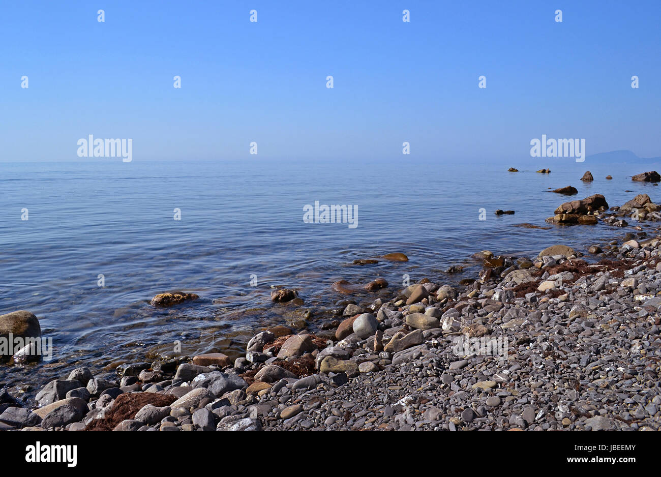 Sea beach of pebbles and stones near the calm sea Stock Photo - Alamy