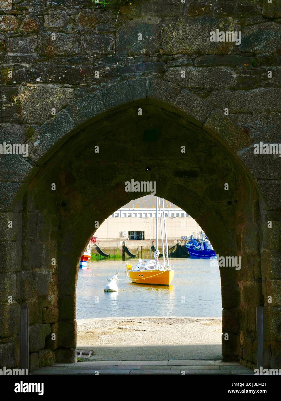 Sailboat with bright, yellow hull as seen through an arch in the ...