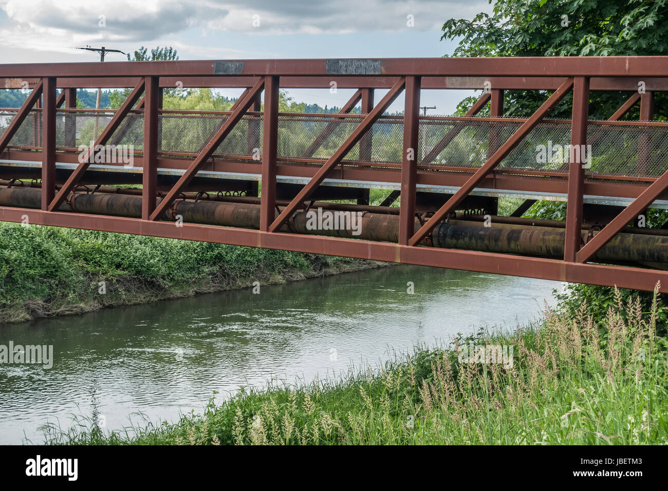 A rusted metal bridge spans the Green River in Kent, Washington Stock ...
