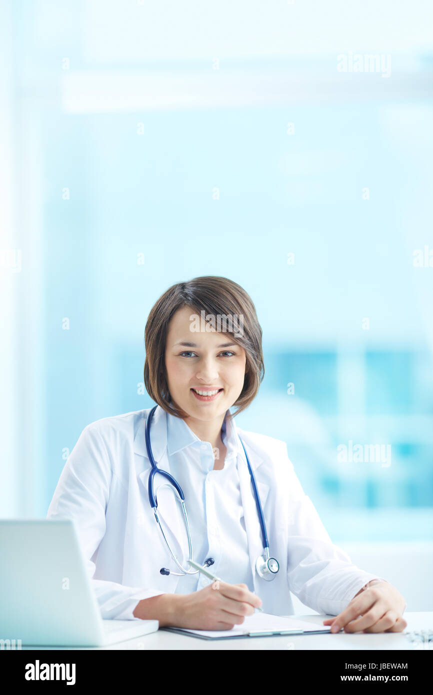 Vertical portrait of a young female doctor looking at camera at her ...