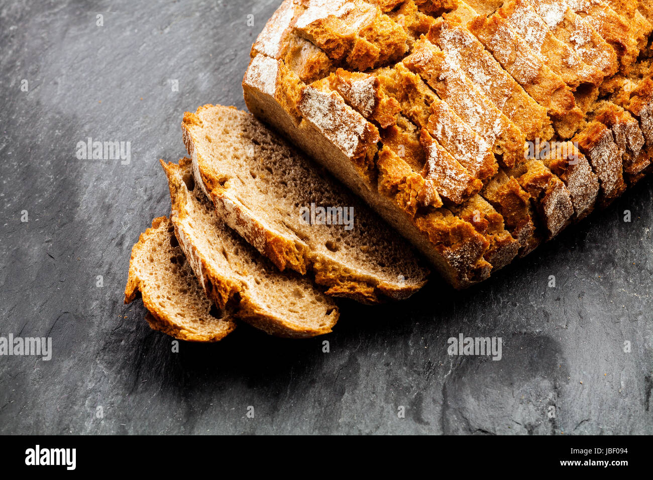 Freshly baked sliced loaf of crusty rye bread viewed from above over a ...