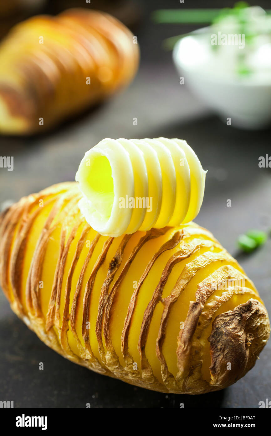 Sliced potato baked in foil and topped with a curl of creamy golden ...