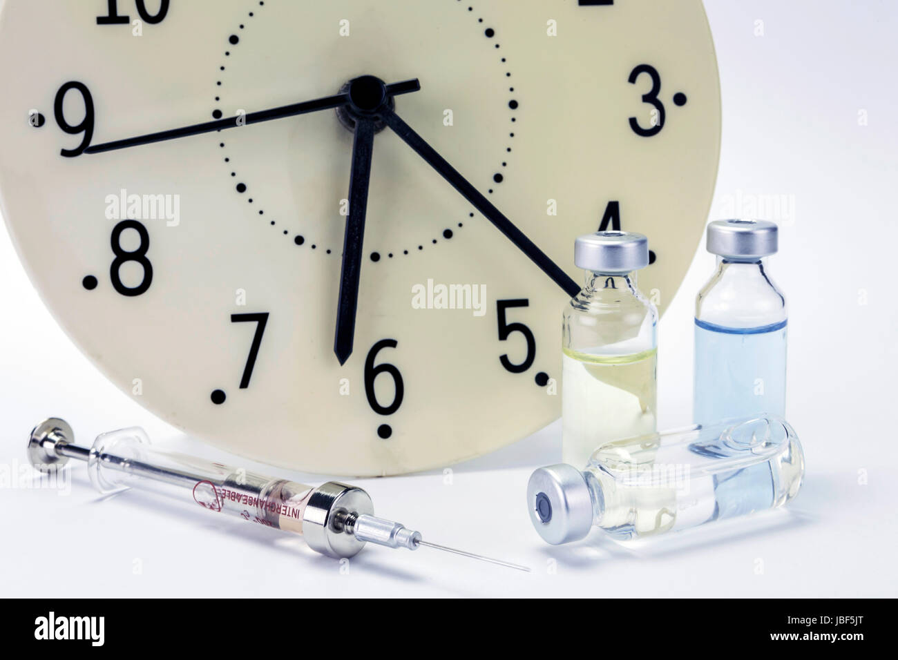 medicine vials and syringe, the clock shows the time of the medication ...
