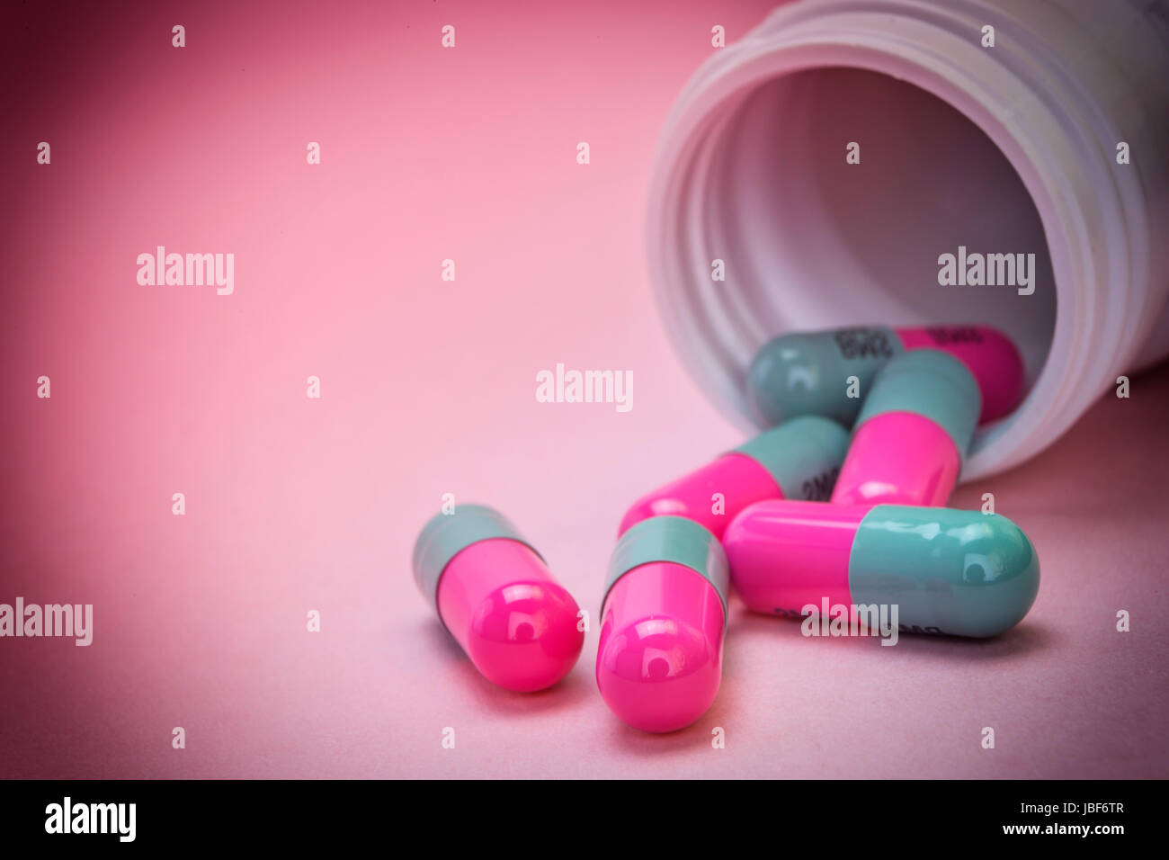 Pills spilling from an open bottle isolated on pink background Stock ...