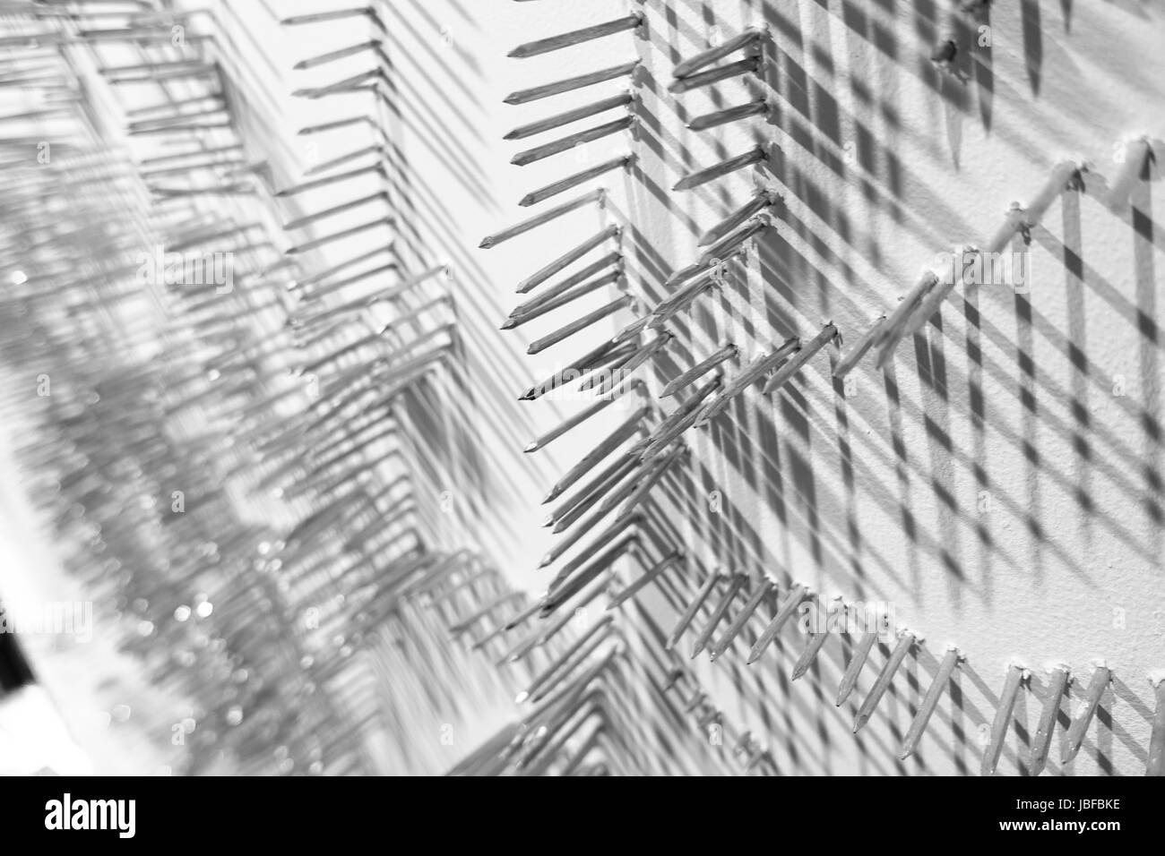 Rows of nails in lines and patterns protrude from a white surface Stock ...