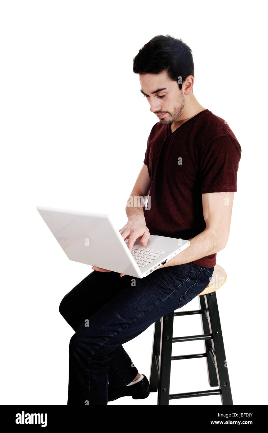 A young man sitting on a chair with his laptop on his lap, isolated on ...