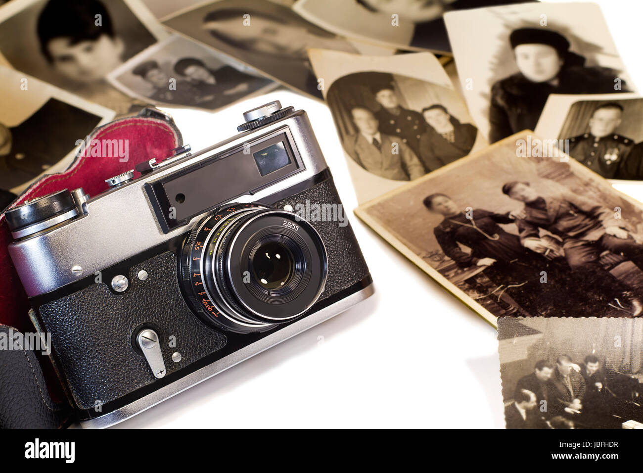The outdated film camera and ancient black white photos on a white ...