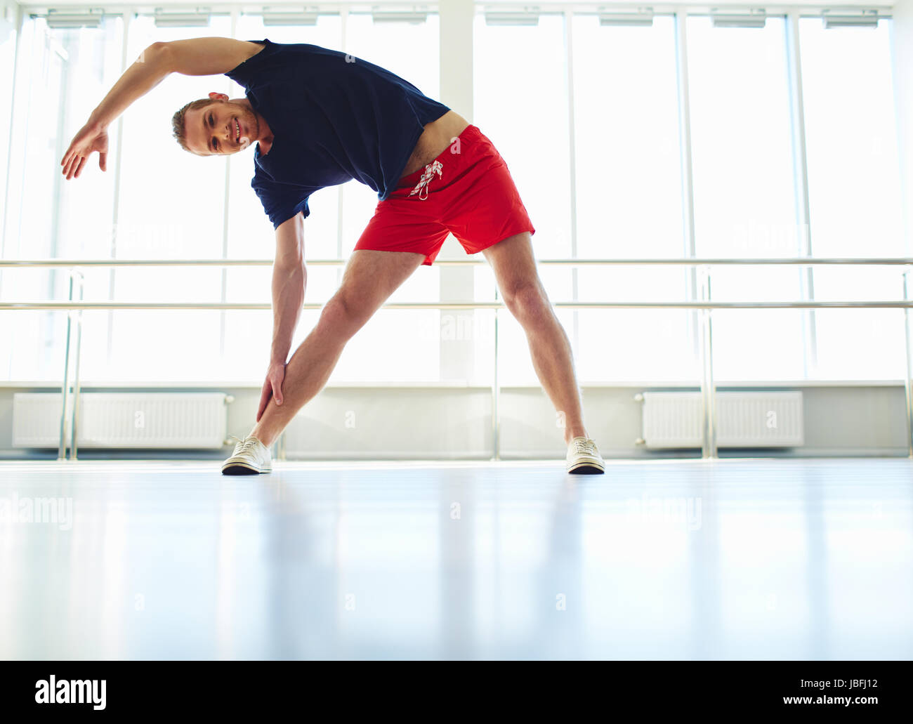 Portrait of happy young man doing physical exercise in gym Stock Photo ...