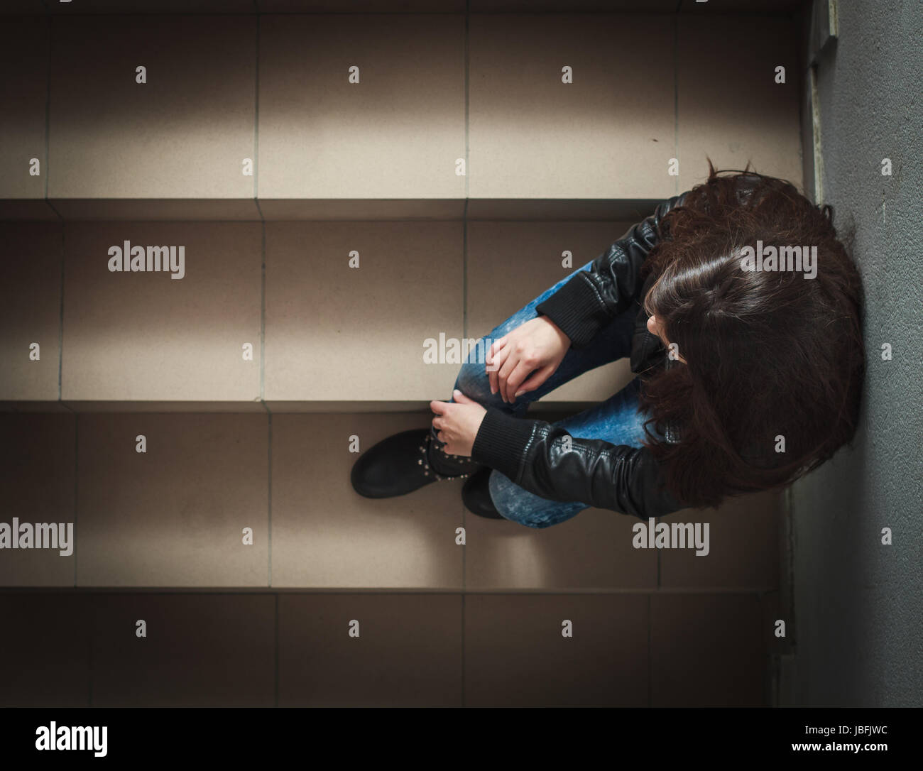 Depressed teenage girl with hands over face sitting on the stairs Stock ...