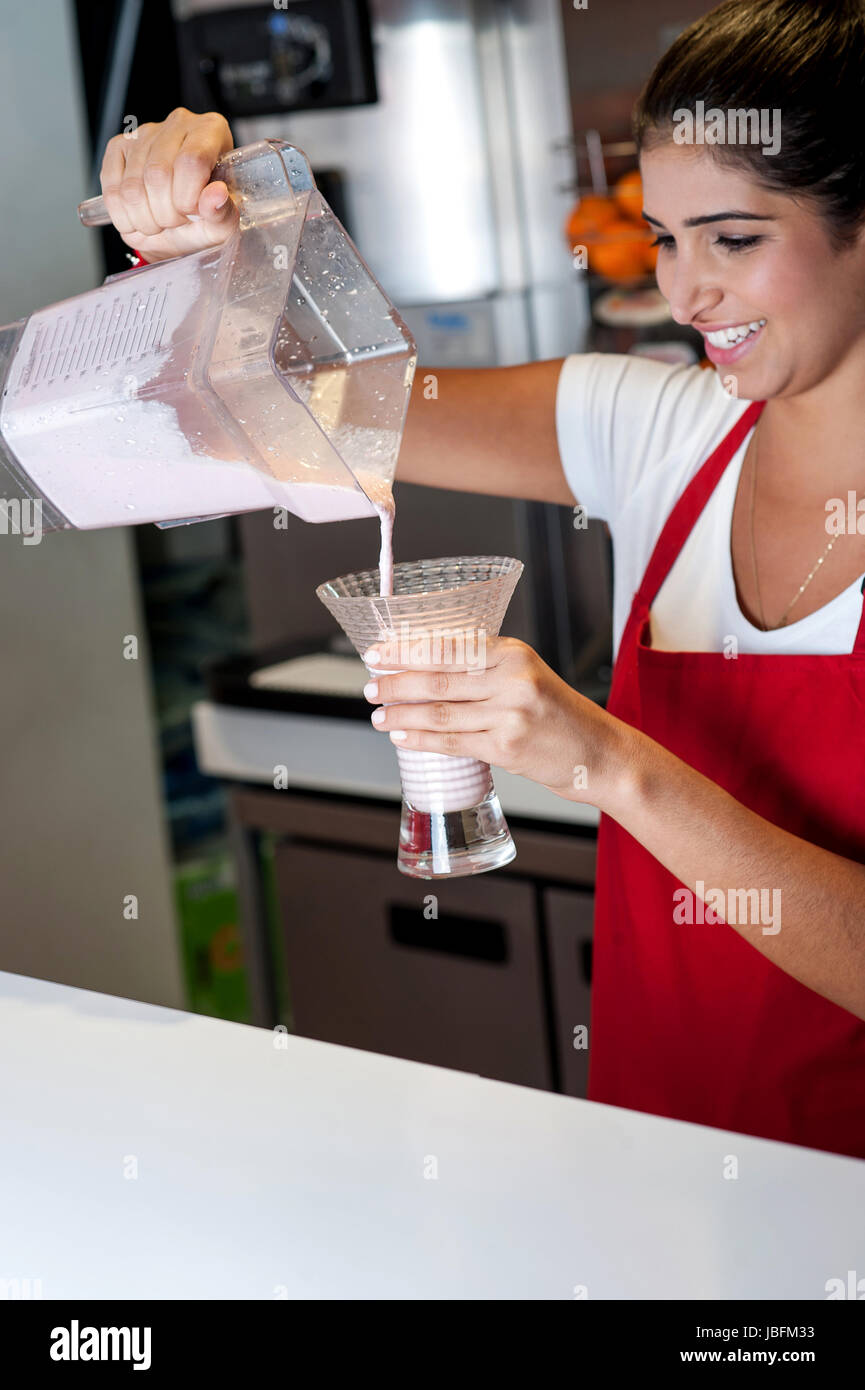 Attractive girl pouring strawberry shake in glass Stock Photo - Alamy