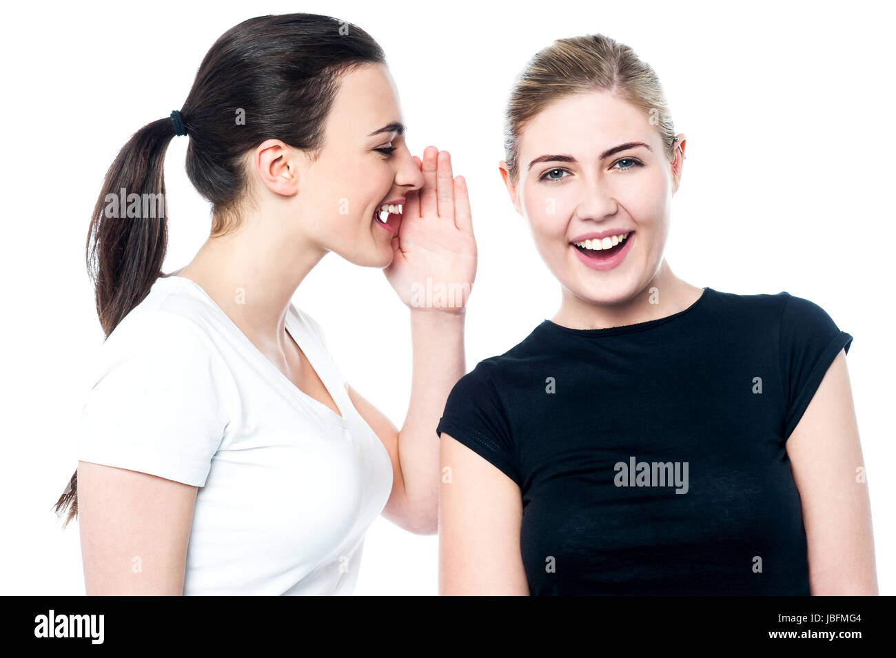 Two attractive girls gossiping isolated on white Stock Photo - Alamy