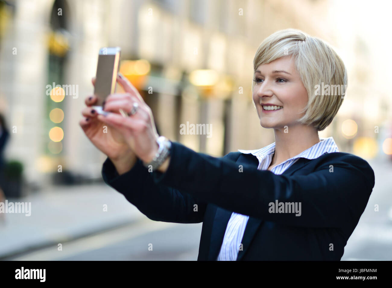Corporate lady clicking her pic, outdoors Stock Photo - Alamy
