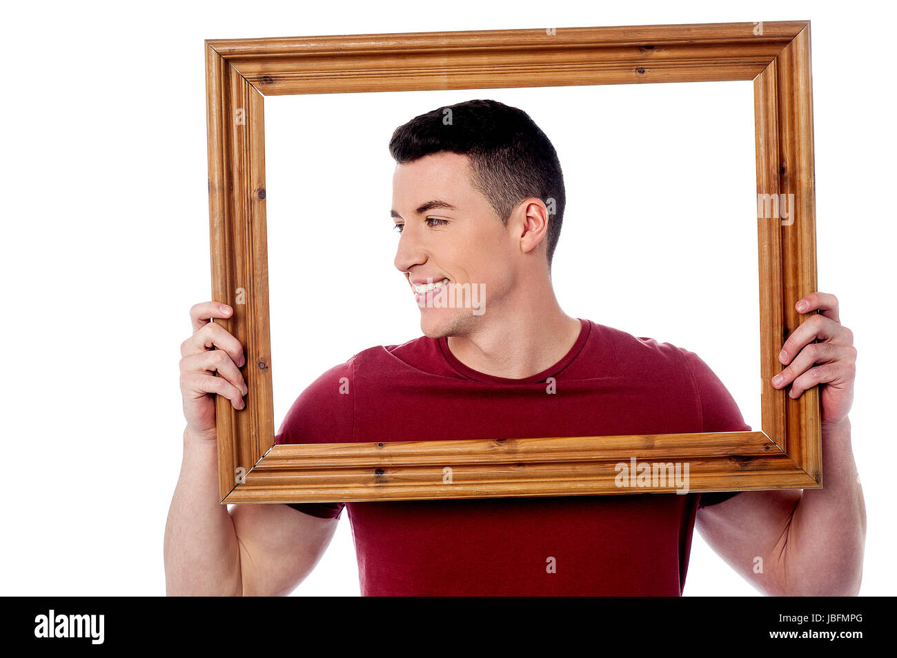 Smiling guy holding wooden picture frame and looking away Stock Photo ...