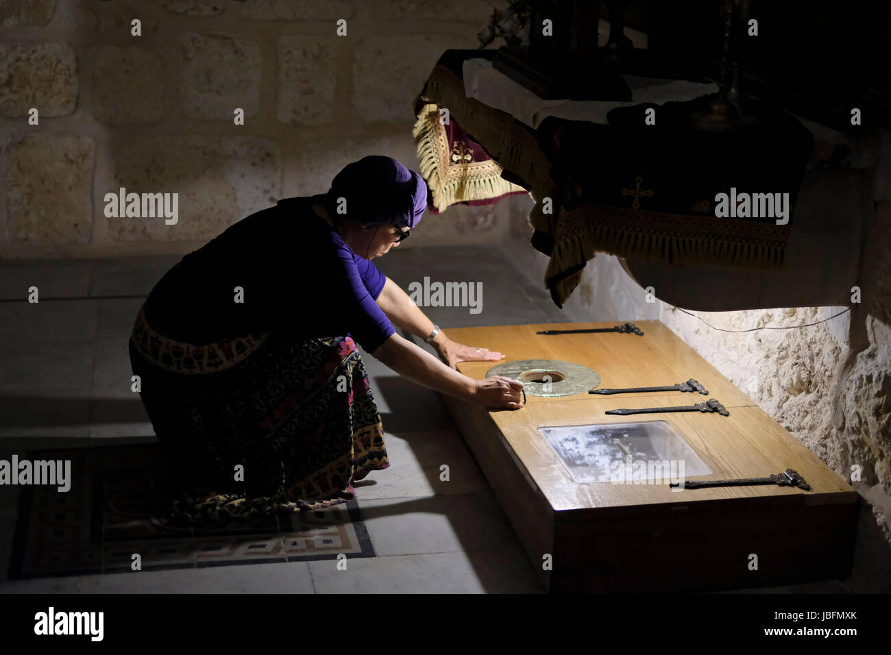 An Eastern Orthodox pilgrim praying at the room of the Holy tree inside ...