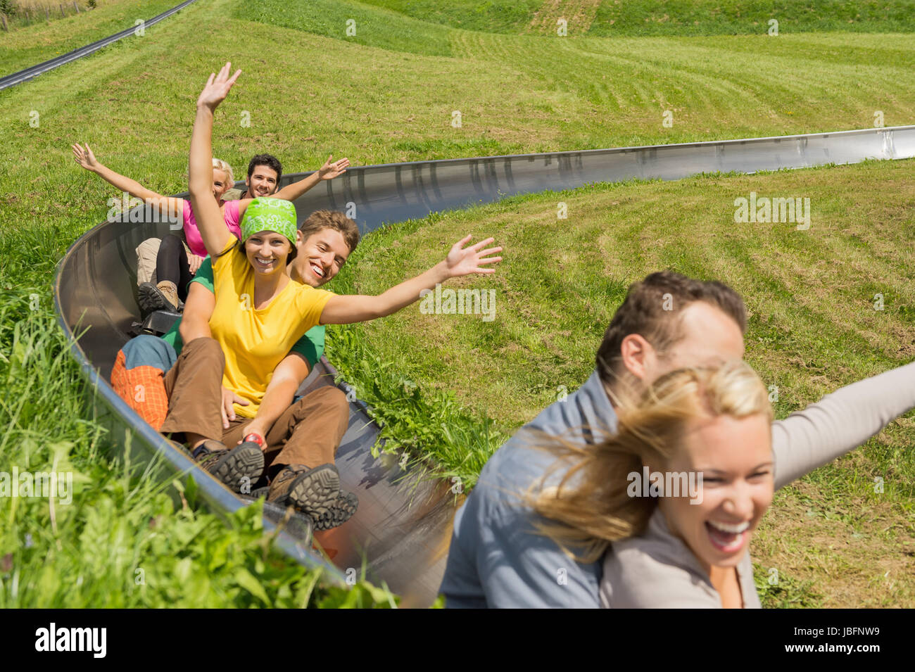 Excited young couples enjoying alpine coaster luge during summer Stock ...