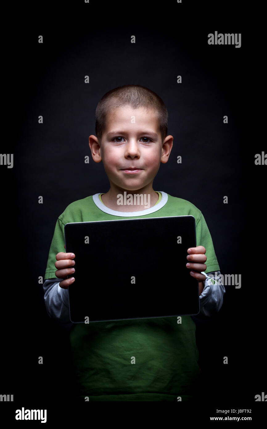 Boy showing tablet computer on black background Stock Photo - Alamy