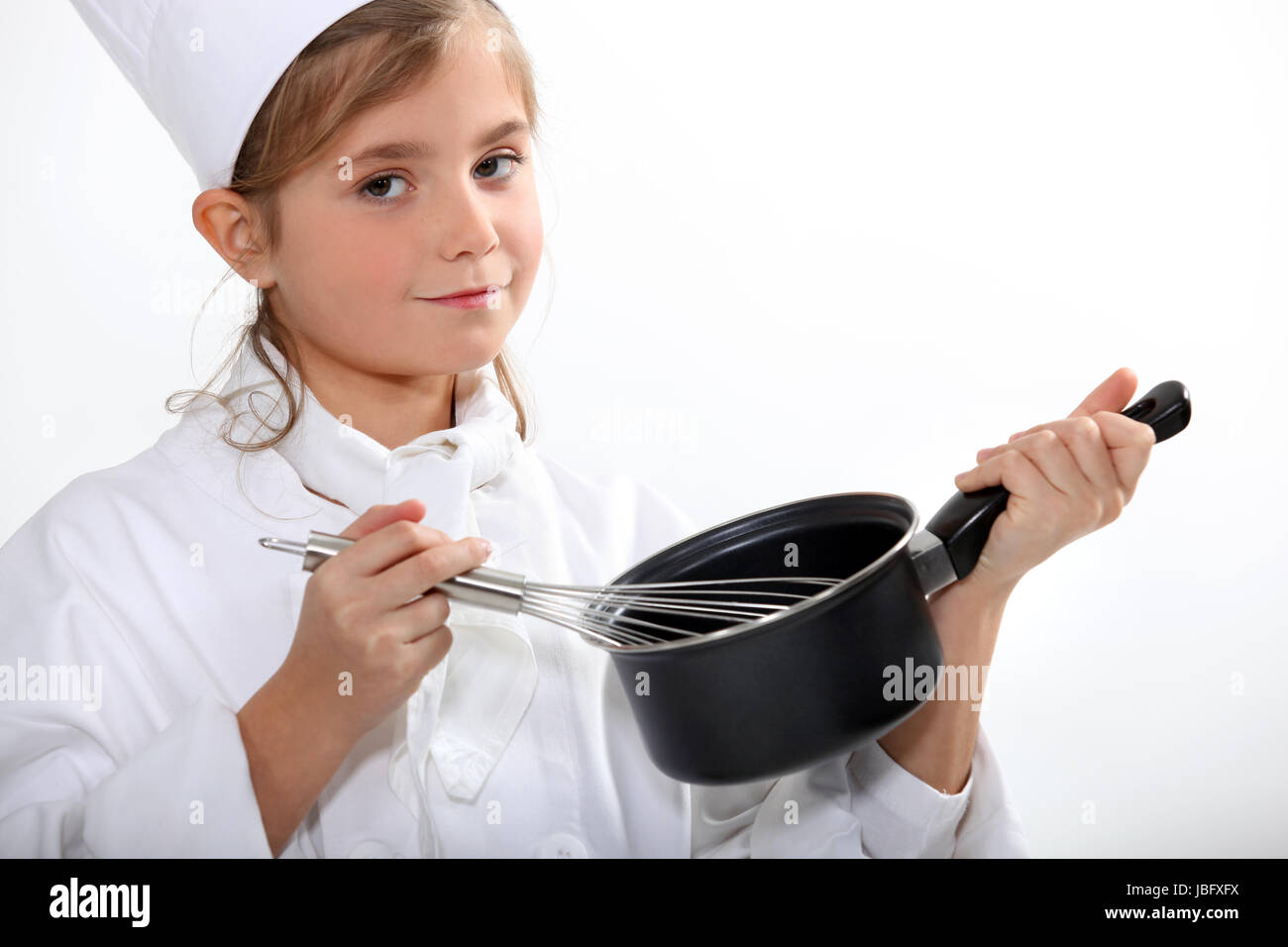 a little blonde girl dressed in chief cook is cooking Stock Photo - Alamy