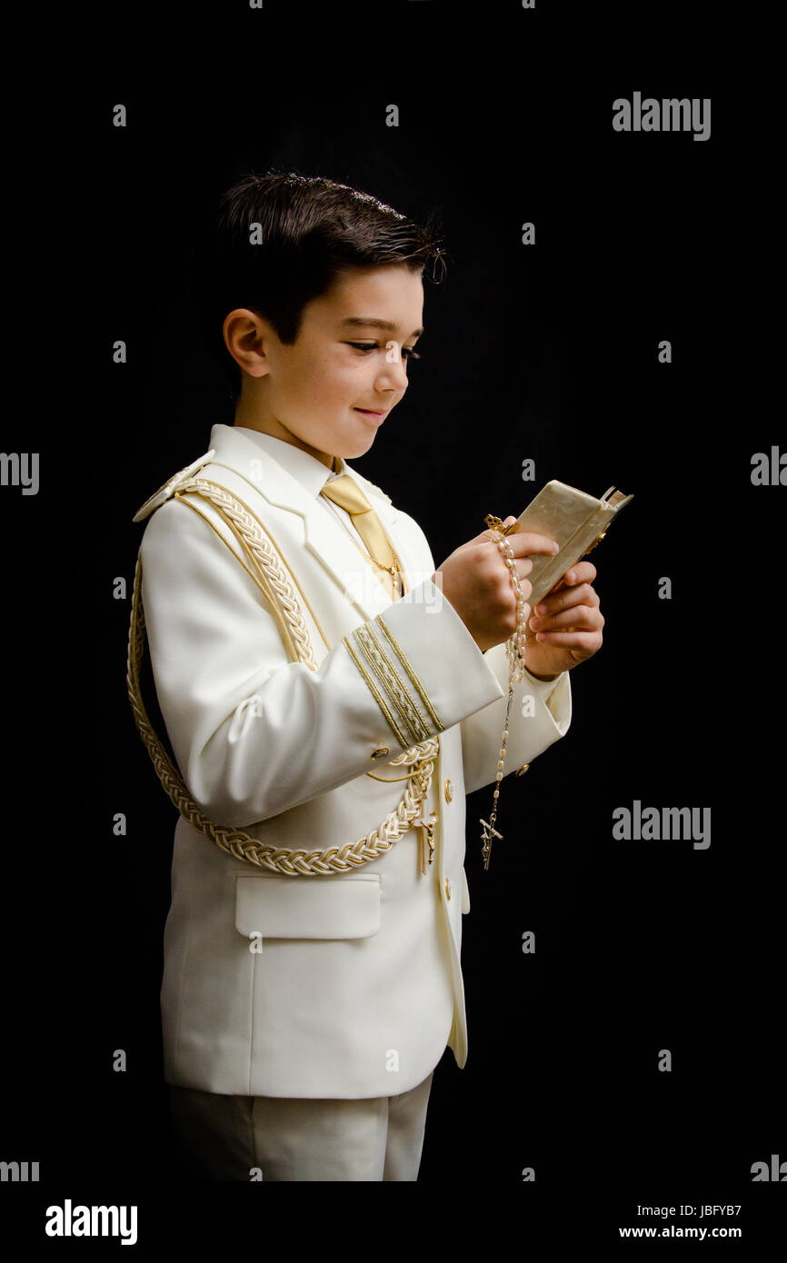 A young boy with rosary and prayer book celebrating his First Holy ...