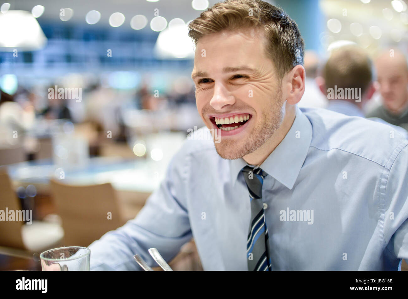 Handsome young man in a cafe and laughing Stock Photo - Alamy