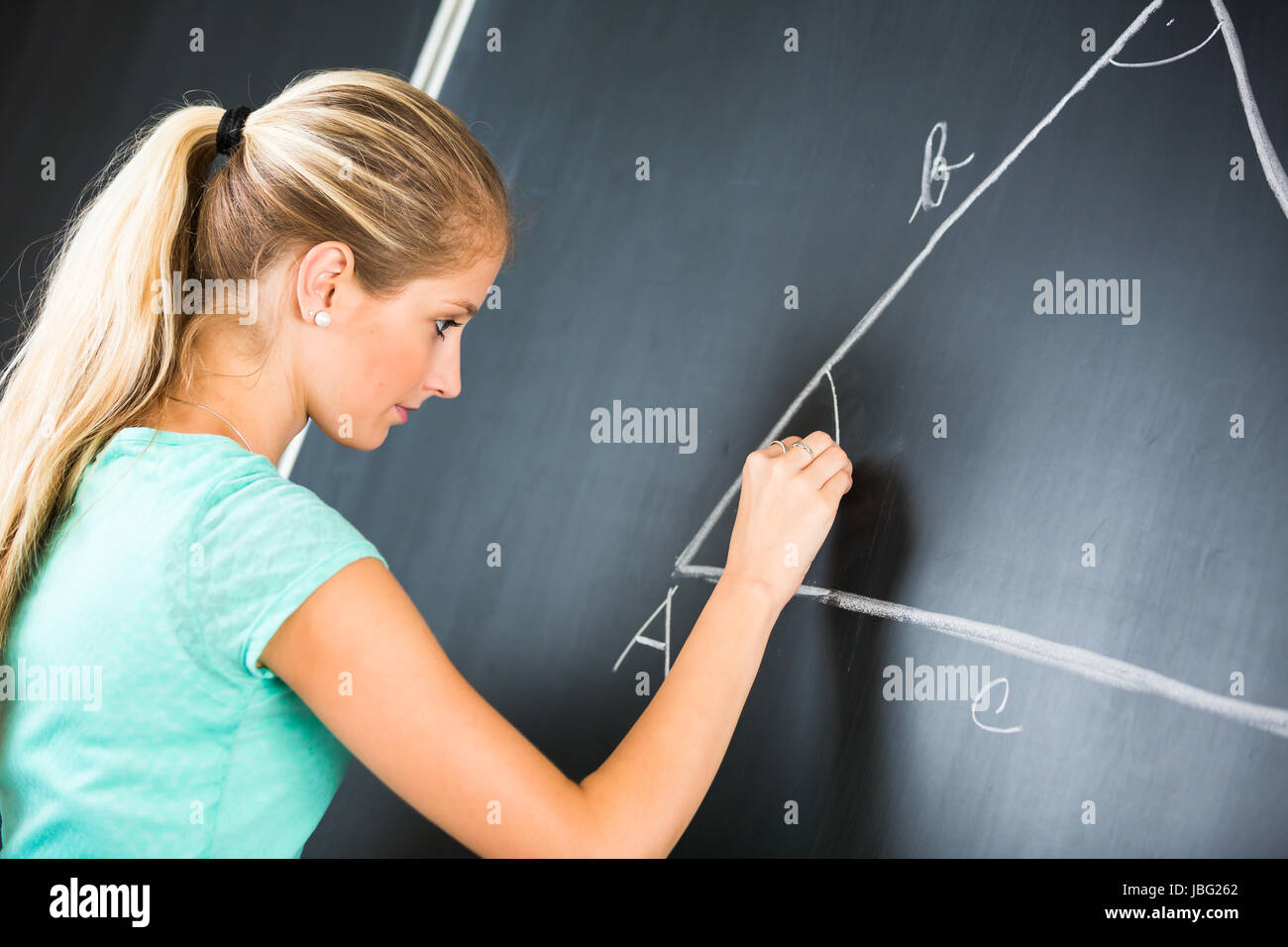 Pretty young elementary school/college teacher writing on the ...