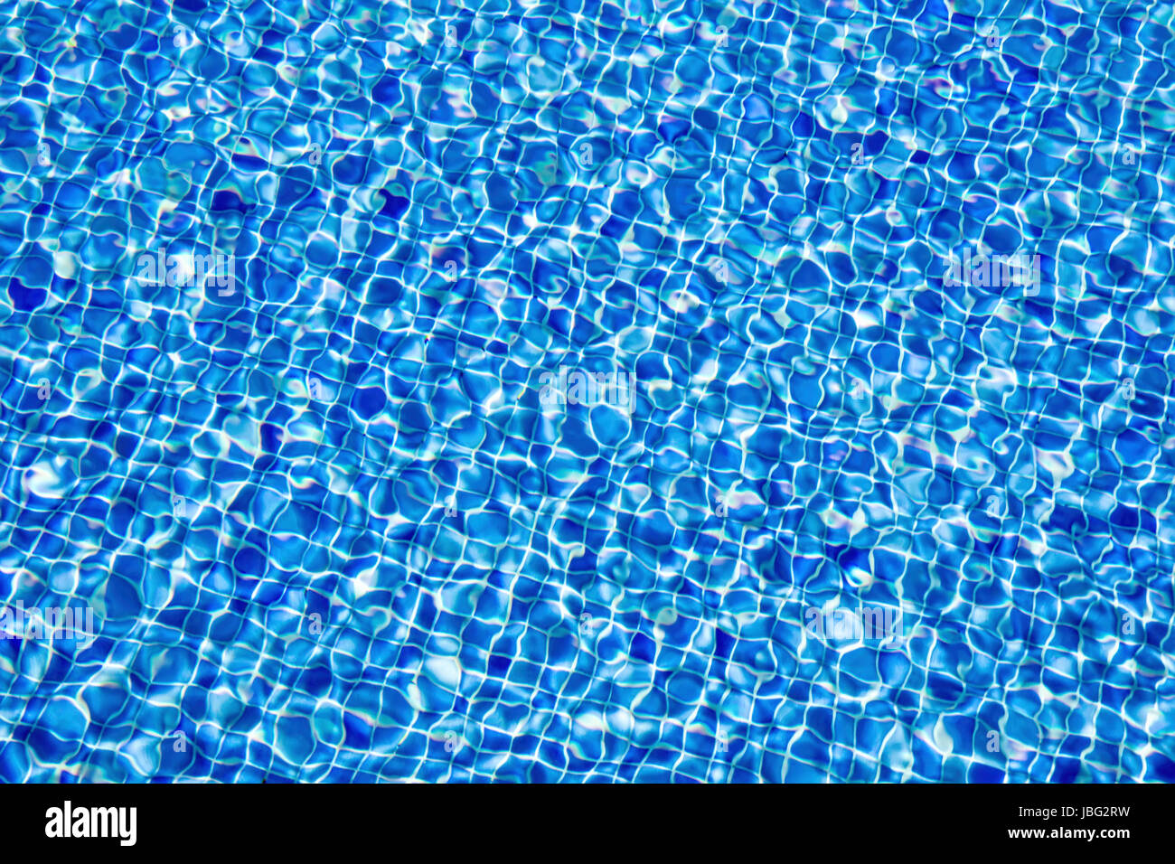 Abstract background of clear water in a dark blue tiled swimming pool ...