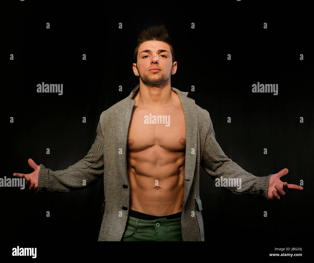 Confident, attractive young man with open jacket on muscular torso ...